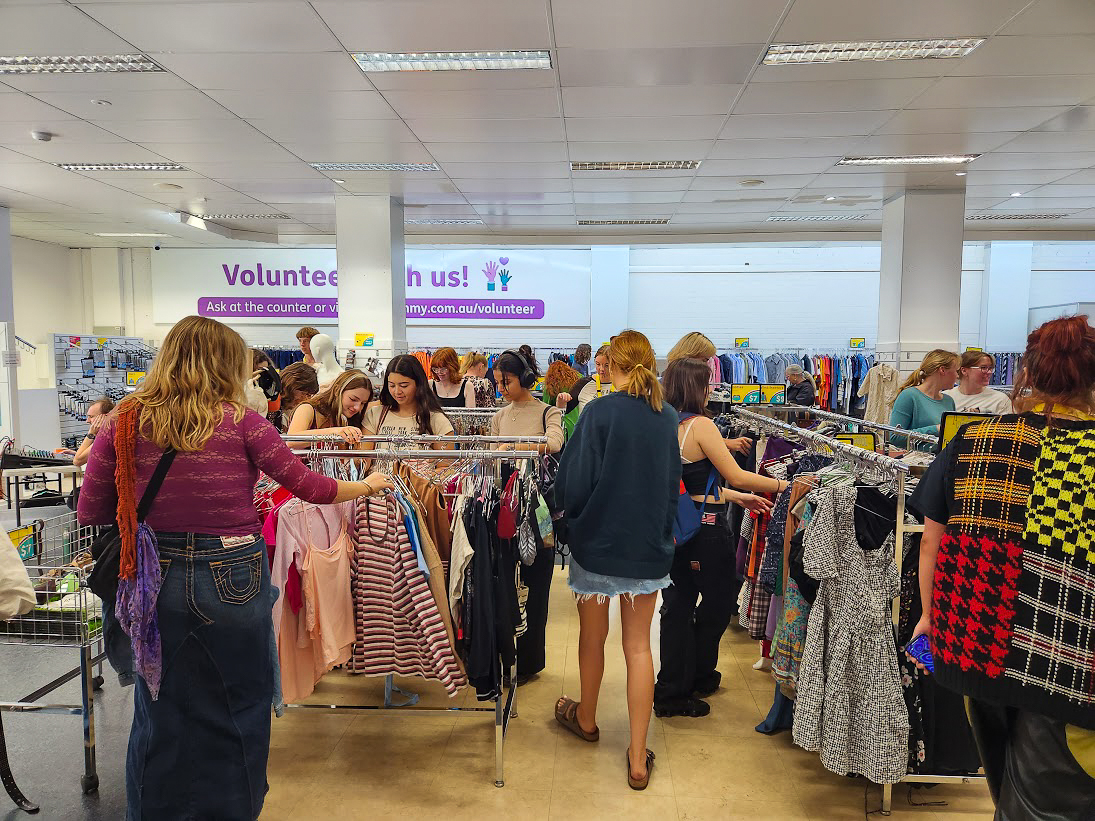 A crowd of people looking through racks of clothes selected by TSS ...